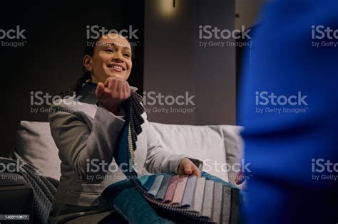 쾌적한 여성 인테리어 디자이너는 홈 복원 디자인 프로젝트를 통해 고객을 돕고 실내 장식품 직물 샘플이있는 대형 팔레트를 보여