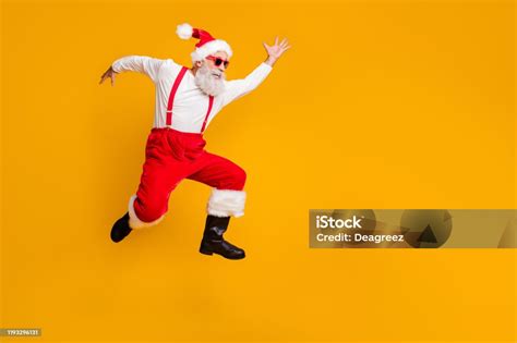 빨간 모자 점프 실행 에서 미친 펑키 회색 머리 수염 할아버지 힙스터의 전신 프로필 측면 사진 X마스 시간 파티 착용 검은 부츠 고립 된 노란색 색상 배경 산타 클로스에