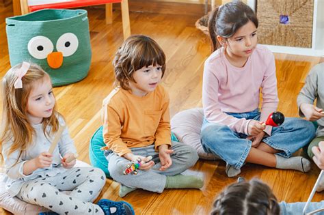 유치원 교사는 다양한 악기와 타악기를 사용하여 음악 수업을 하는 바닥에 앉아 있습니다 2 3 살에 대한 스톡 사진 및 기타 이미지 2 3 살 30 34세 4 5세