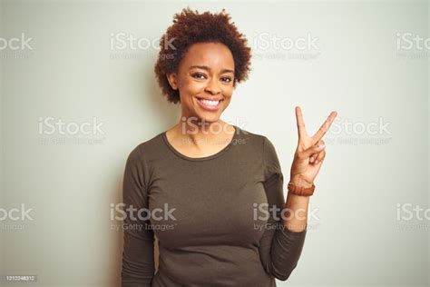 고립 된 배경 위에 아프리카 머리를 가진 젊은 아름다운 아프리카 계 미국인 여성은 승리의 기호를하고 카메라에 윙크 행복한 얼굴미소 2번 긍정적인 감정 표현에 대한 스톡 사진