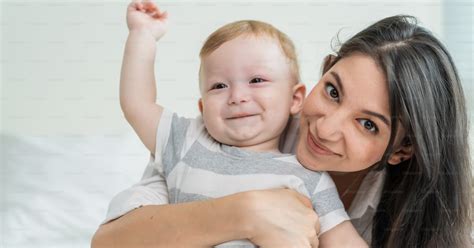 백인 행복한 가족의 초상화 침실에서 카메라를 봐 젊은 매력적인 여성 부모 잠옷을 입은 어머니는 어린 남자 아이와 함께 침대에 앉아 집에서 아침 기상 활동을 즐깁니다