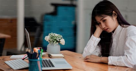 지루한 아시아 여성 노동자는 사무실 책상에 누워 휴대 전화와 노트북 화면을보고 문제 해결 동기 부여되지 않은 사업가 검색 영감 단조로운 작업에 지쳤습니다 동기 부여