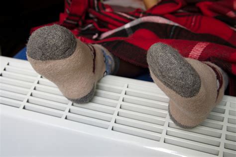 모직 담요를 가진 아이가 전기 히터 위에 발을 따뜻하게 합니다 감기와 독감의 상징적 인 이미지 추운 계절에 가정 난방 클로즈업