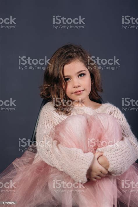 가벼운 스웨터 및 얇은 명주 그물 치마에 갈색 머리를 가진 작은 아름 다운 소녀 스튜디오입니다 공주는 사진 작가 대 한 포즈