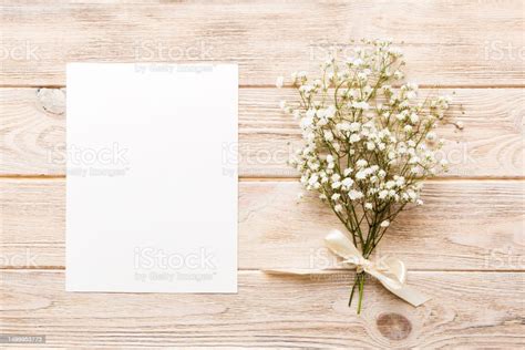 하얀 종이 목록과 꽃이 있는 결혼식 모형은 컬러 테이블 위에 평평하게 놓여 있다 빈 인사말 카드와 봉투 아름 다운 꽃 무늬입니다