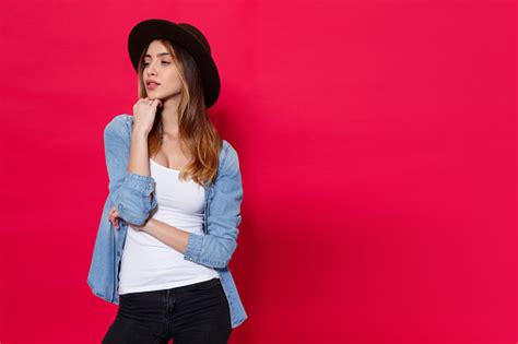 캐주얼 한 옷과 갈색 모자에 세련 된 소녀 텍스트에 대 한 장소와 함께 밝은 빨간색 배경에 스튜디오에서 Attitudine과