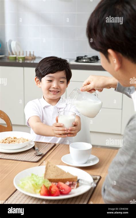 Father pouring milk for son at table Stock Photo - Alamy