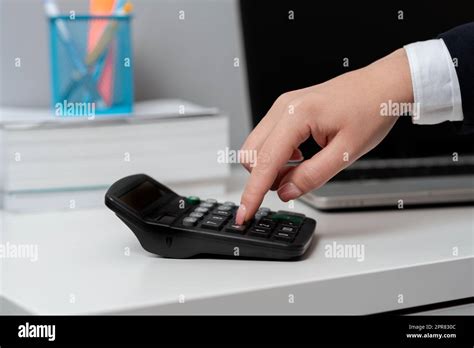Businesswoman Pressing On Calculator With One Finger On Desk With Lap Top And Books Executive