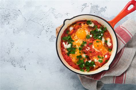 샤크슈카 밝은 회색 슬레이트 돌 또는 콘크리트 배경에 철 프라이팬에 야채와 계란 튀김 이스라엘의 전통 요리 늦은 아침 식사 개념 상단 보기 배너 0명에 대한 스톡 사진 및