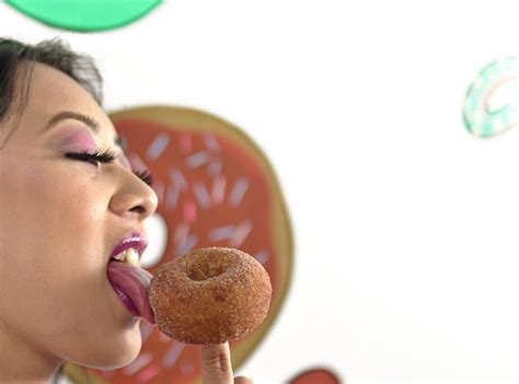 Premium Photo Close Up Of Woman Licking Sweet Food Against Wall