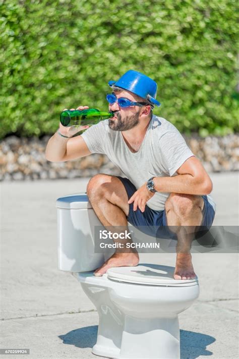 길 중간에 설치 된 화장실 중간 고글에 수염된 남자 그의 머리에 팬을 요리 하는 그의 손에 화장실 브러시입니다 맥주를 마시는 Publicity Event에 대한 스톡 사진