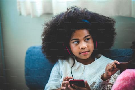 빨간 하트 모양의 쿠션 베개를 들고 집에서 엄마와 놀고 있는 행복한 작은 혼합 아피칸 소년 귀여운 소년은 행복을 숨길 수 없어 엄마와 함께 있는 동안 미소를 짓고