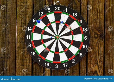 darts hanging on a wooden wall with a dart stuck in the center stock