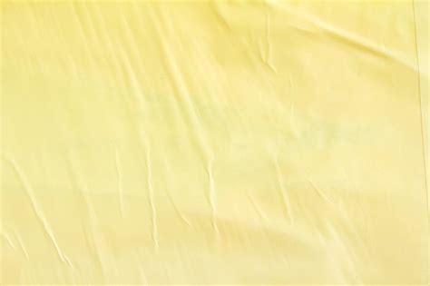 파스텔 노란색 구겨진 포스터가 거리 광고판에 붙어 있습니다 거친 표면 질감 배경 창백한 노란색 물결 모양의 종이 플래카드입니다 텍스트의 공간을 복사합니다 노랑에 대한 스톡