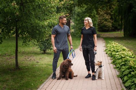 Joyful Couple With Their Two Dogs Walking In Park Stock Image Image