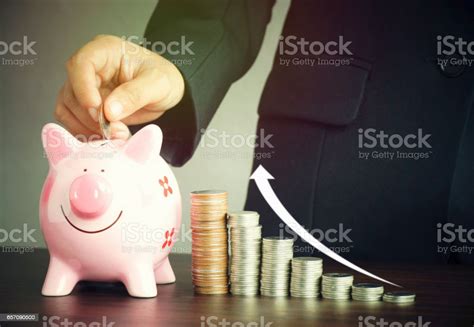저장 핑크 돼지 저금통과 동전 파란색 배경에 성장 개념의 더미에 돈을 넣어 사업가 사업에 투자의 손 경제에 대한 스톡 사진 및