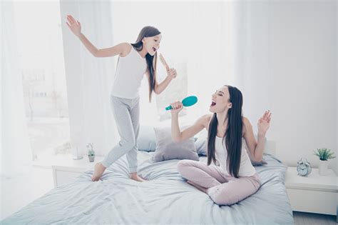 두 개의 좋은 아름다운 아름다운 재미 펑키 펑키 평온한 장난 쾌활한 쾌활한 긴 머리 사람들이 밝은 흰색 인테리어 방에 히트 노래 팝 멜로디를 기뻐 하는 리넨 시트에 재미를