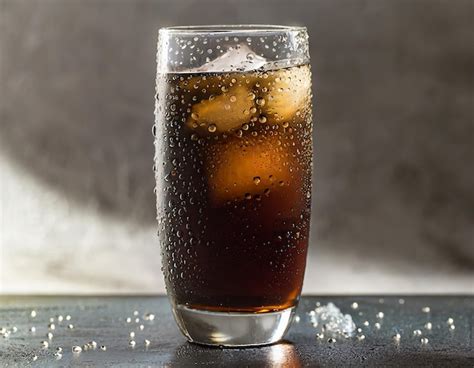 Glass With A Dark Colored Carbonated Drink On A Gray Background With Drops Of Refreshing Water