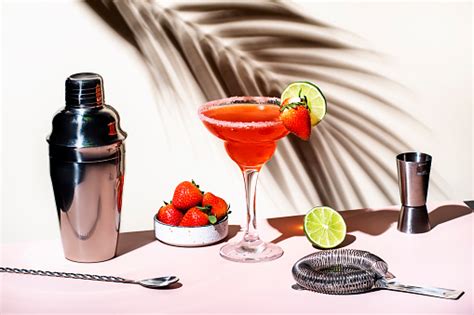 딸기 마가리타 여름 칵테일 음료는 실버 데킬라 라임 주스 리큐어 신선한 딸기 및 소금 테두리가 있는 유리에 얼음을 담았습니다 베이지색 분홍색 배경 하드 라이트 그림자 패턴