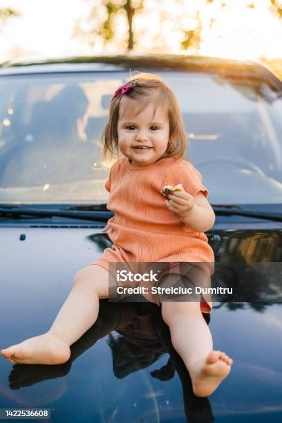 언덕에 주차 된 자동차 후드에 앉아있는 어린 아기 소녀의 정면보기 여름 방학 재미 아름다운 소녀 초상화 18 23 개월에 대한