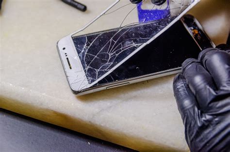 기술자 또는 엔지니어가 책상에서 새로운 부품을 수리하거나 교체하기 위해 깨진 스마트 폰을 여는 엔지니어 감자 칩에 대한 스톡