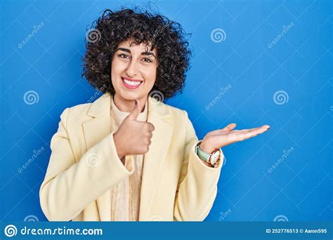 Jovencita Morena Con Pelo Rizado Sobre Fondo Azul Mostrando Mano De Palma Y Haciendo Un Gesto