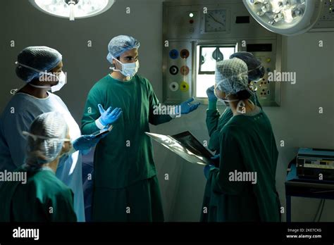 Diverse Group Of Male And Female Surgeons In Discussion In Operating Theatre Before Operation