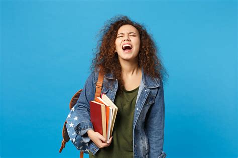 데님 옷에 젊은 슬픈 아프리카계 미국인 소녀 사춘기 학생 배낭은 파란색 배경 스튜디오 초상화에 고립 된 책을 보유 고등학교 대학 대학 개념에서 교육 복사 공간을 모의 합니다