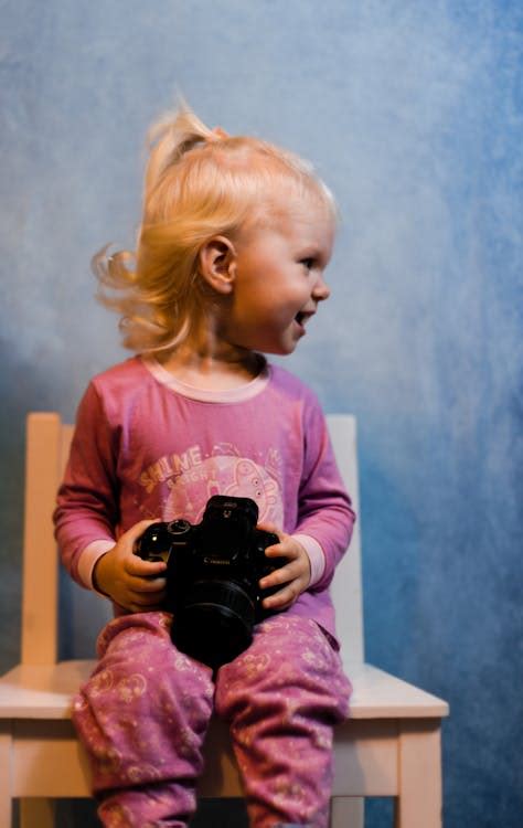 의자에 카메라를 들고 웃는 유아 · 무료 스톡 사진