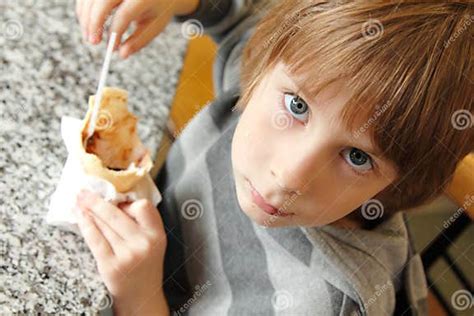 Мальчик есть мороженое в кафе Стоковое Изображение изображение