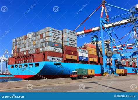 Port Dock With Container Ship And Various Brands And Colors Of Shipping Containers Stacked In A