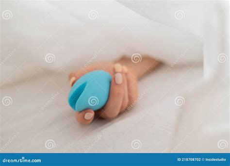 A Faceless Woman Lies In Bed Under A Blanket Holding A Clitoral