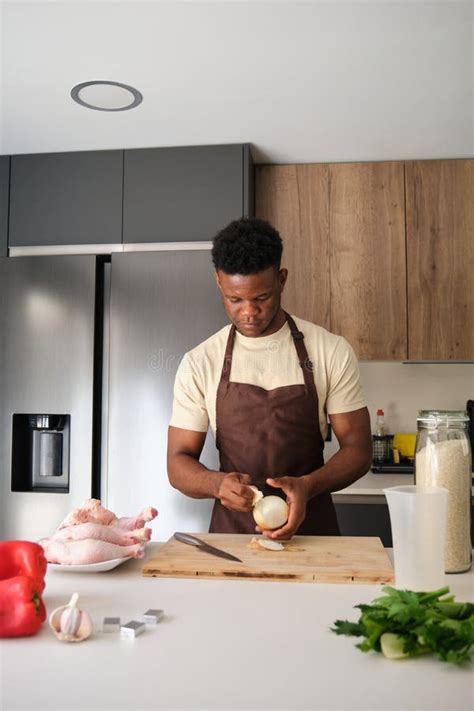 Joven Africano Pelando Cebolla Para Preparar La Receta De Pollo Imagen