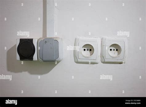 Two Electrical Outlets And A Switch Are Mounted On A Simple White Wall
