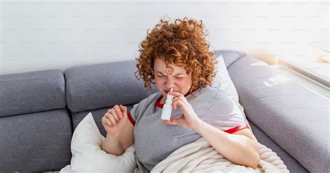 여자는 알레르기가 있고 그녀는 자신을 돕기 위해 비강 스프레이를 사용하고 있습니다 비강 스프레이를 사용하는 여성 감기에