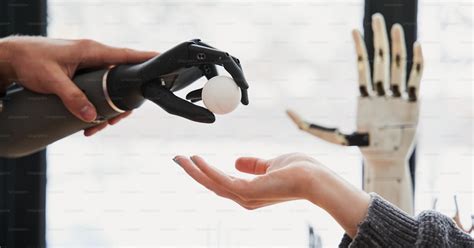 가져 가세요 엔지니어의 클로즈업 초상화는 팔다리의 기능을 테스트하는 동안 생체 공학 손으로 테니스 공을 여성 동료에게 전달합니다 스톡 사진 사진 Unsplash의