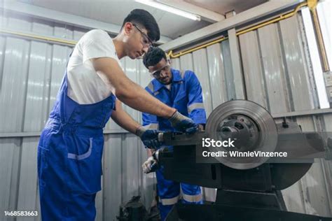 금속 선반 기계를 사용하는 다양성 정비사 또는 금속 세공인은 자동차 수리 차고에서 자동차 디스크 브레이크를 연마합니다 자동차