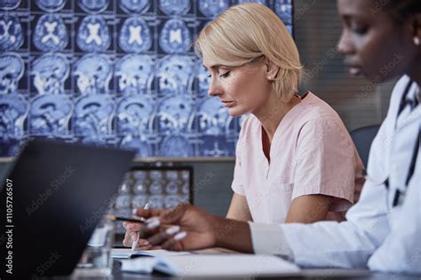 Female Radiologist Writing Notes In Notebook Thoroughly Studying