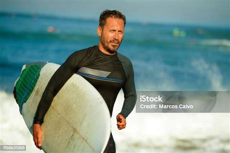 라이프 스타일 해변 여름 수상 스포츠와 휴일을 즐기는 서핑 후 행복 하 고 쾌활 한 서핑 보드를 운반 하는 네오프렌 수영복에 잘생긴 매력적인 서퍼 남자의 초상화 40 49