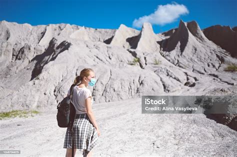 젊은 금발 의 여자는 코비드 19 예방을위한 얼굴 보호 마스크를 입고 흰색 산에 대해 걷고 배낭을 가진 젊은 학생 여행자 여행자 관광객 코로나 바이러스 및 국내 관광 개념