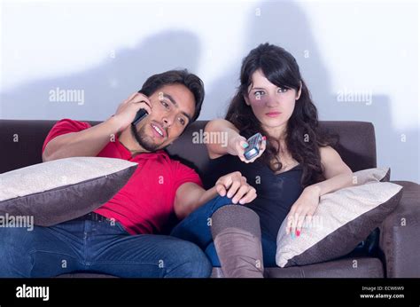 Bored Girlfriend Watching Tv While Boyfriend Chats On The Phone Stock