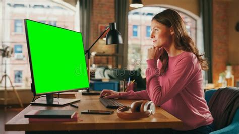 Young Pretty Female Working From Home On Desktop Computer With Green Screen Mock Up Display