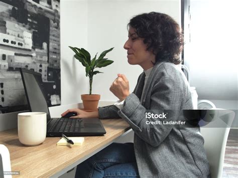 그녀의 노트북 앞에서 승리를 축하하는 현대 비즈니스 백인 여성 그녀는 포스트 그 과 그녀의 책상에 커피 한 잔을 가지고 갈색 머리에 대한 스톡 사진 및 기타 이미지 Istock