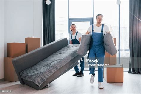무거운 소파를 들고 방에서 실내에서 일하는 파란색 유니폼을 입은 두 명의 젊은 이주 남자에 대한 스톡 사진 및 기타 이미지 남자 서비스 소파 Istock