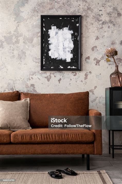 갈색 소파 모형 포스터 프레임 검은 화장실 말린 꽃이있는 유리 꽃병 베이지 색 베개 및 개인 액세서리가있는 거실의 현대적인 구성 가정 장식 템플렛 0명에 대한 스톡 사진 및