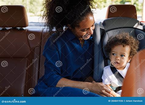 Smiling Mother Looking At Her Little Son While Sitting On Backseat