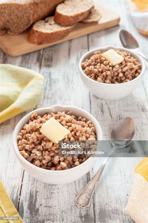 버터 조각이 있는 흰색 둥근 접시에 삶은 메밀 죽 배경 호밀 빵 가벼운 나무 배경에 갈색에 대한 스톡 사진 및 기타 이미지 갈색 고명 끓는 물에 삶기 Istock