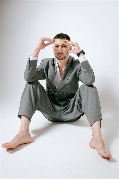 Handsome Man In Grey Suit Sits On The Floor Barefoot Shoot In Studio