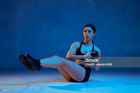 네온 빛에 파란색 스튜디오 배경에 연습 백인 젊은 여성 운동 선수 가냘픈에 대한 스톡 사진 및 기타 이미지 가냘픈 건강한 생활방식 건축하기 Istock