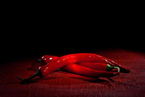 고추가 닫힙 칠레 고추 나무 보드에 붉은 배경에 야채 극적인 빛을 예술적 효과로 대조합니다 후추 근처의 텍스트를 위한 공간과